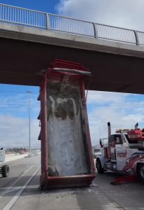 Truck’s dump box gets stuck under bridge after leaving construction site